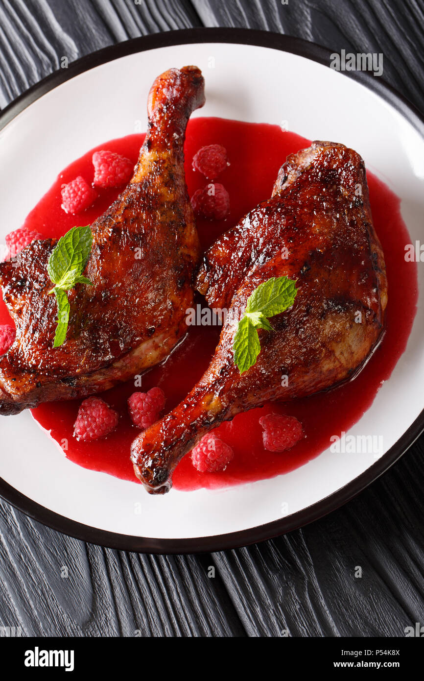 Fried duck leg with raspberry sauce decorated with mint closeup on a ...