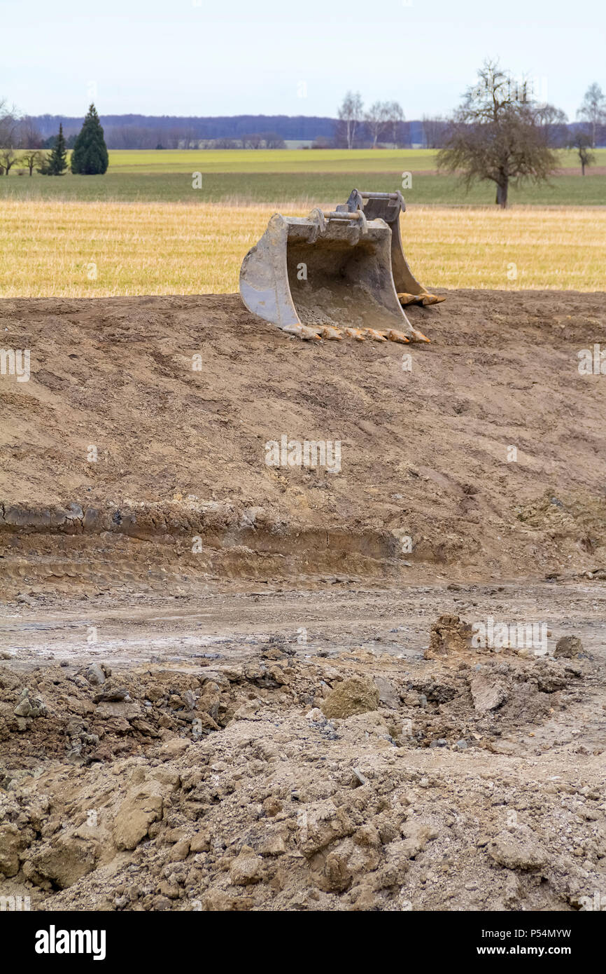 rural landscape including two used dredger buckets on loamy ground ...
