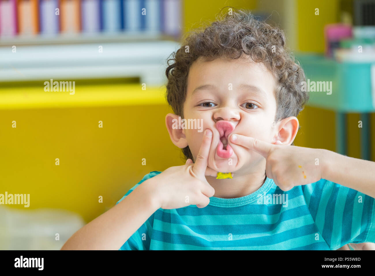 Portrait of Caucasious boy play a fun face in classroom at kindergarten ...