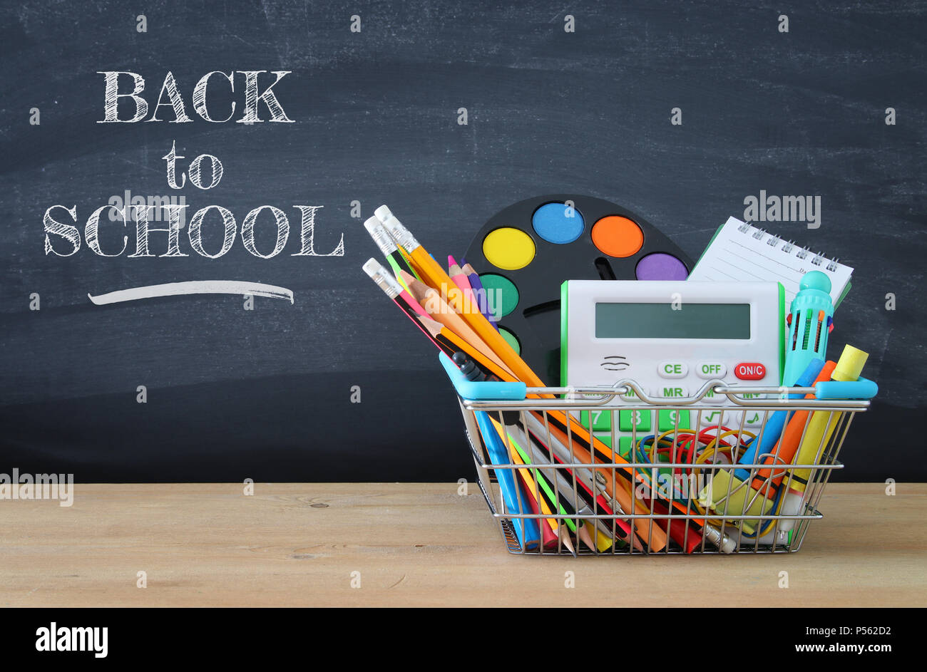 Shopping cart with school supply in front of blackboard. Back to school ...