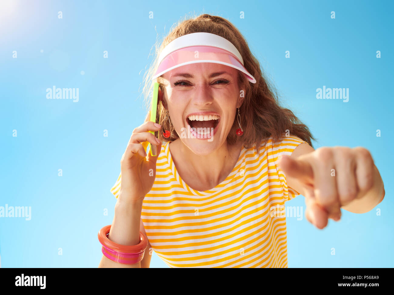 smiling active woman in yellow shirt against blue sky speaking on a ...