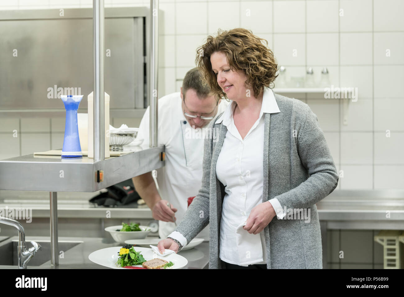 Service woman taking food from chef in restaurant kitchen Stock Photo ...