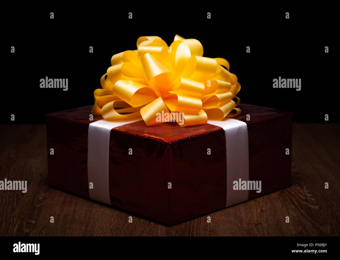 one large red gift box with yellow bow on a wood background Stock Photo ...