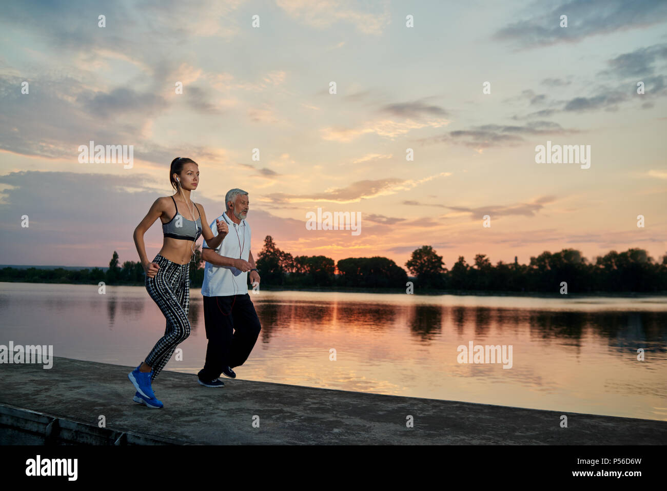 Pretty girl's and senior man's evening scamper while sunset. Fitness ...