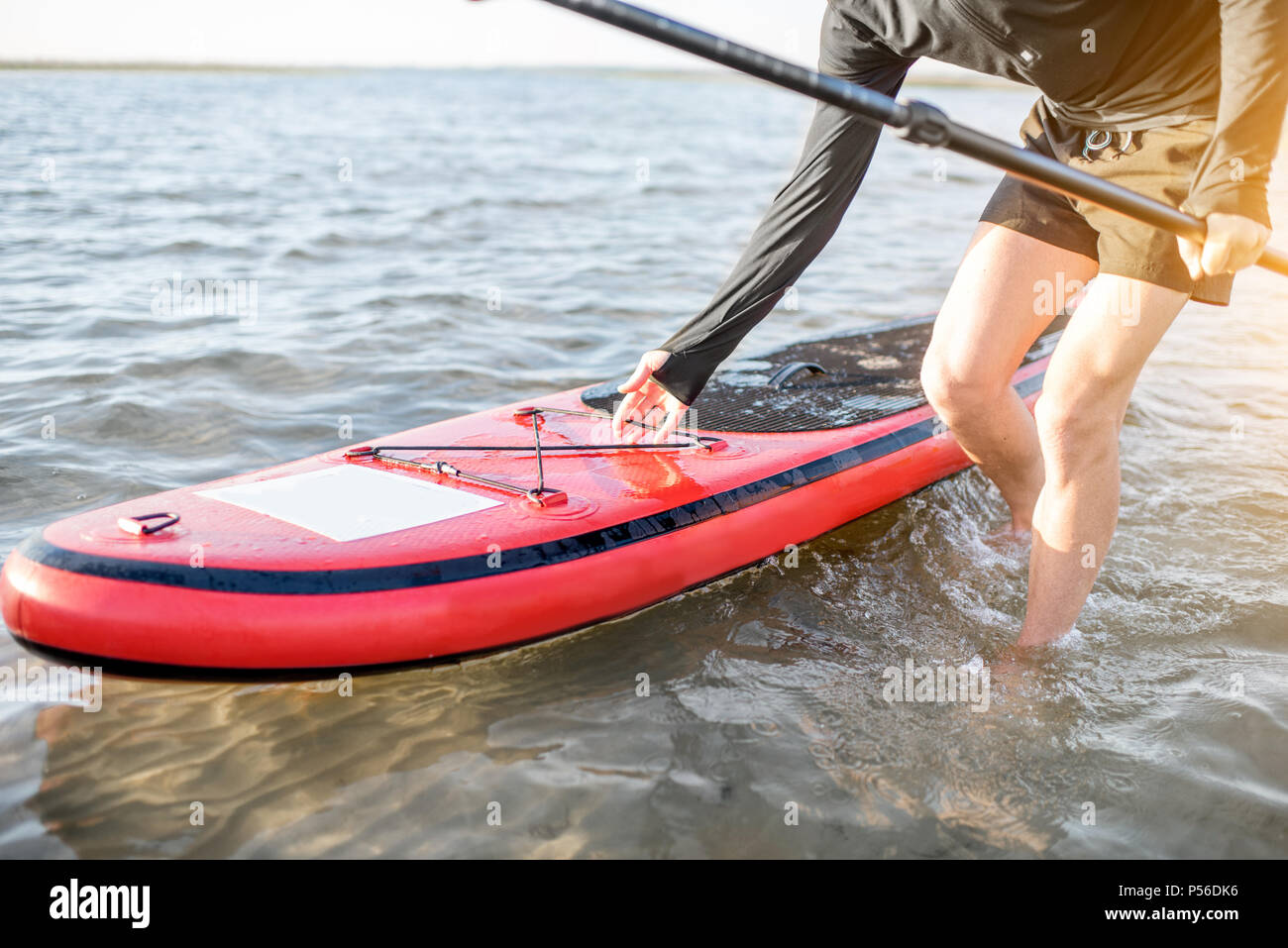 Man carrying paddleboard on the water Stock Photo - Alamy