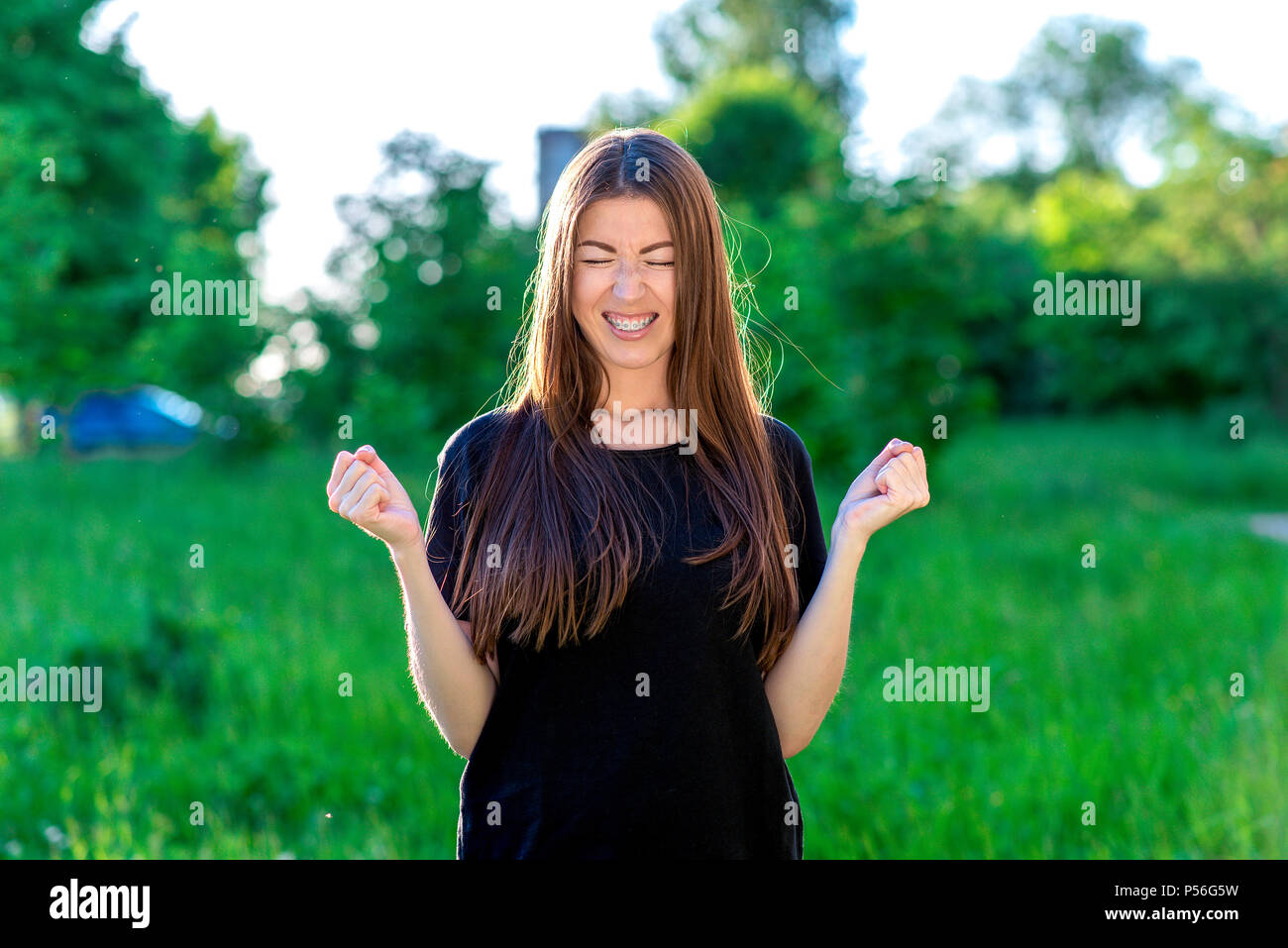 A brunette happy girl is smiling holding her fists for good luck. He ...