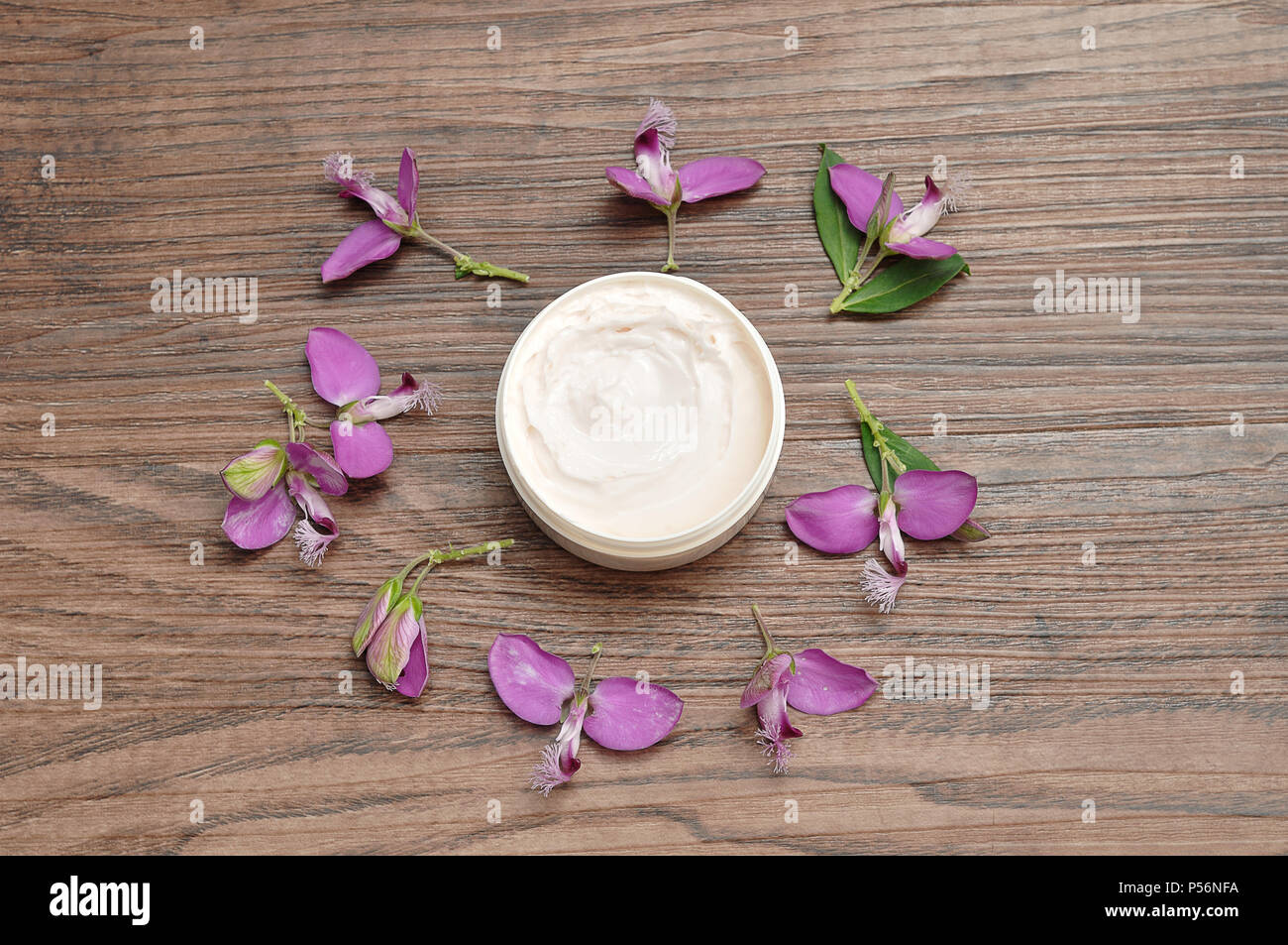 A tub of hand lotion displayed with small purple flowers Stock Photo ...