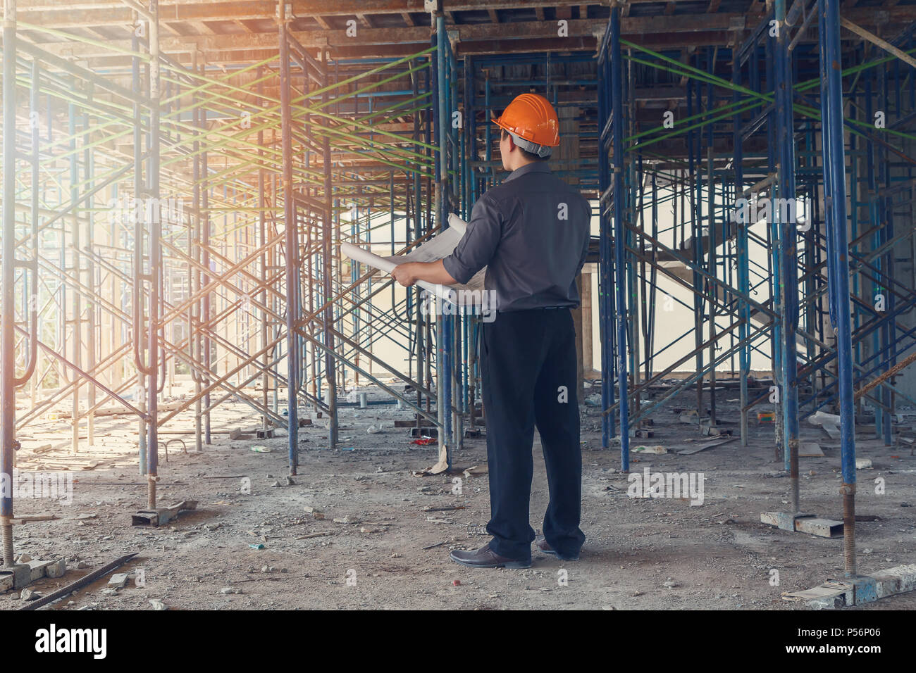Engineer with blueprint in building construction site Stock Photo - Alamy