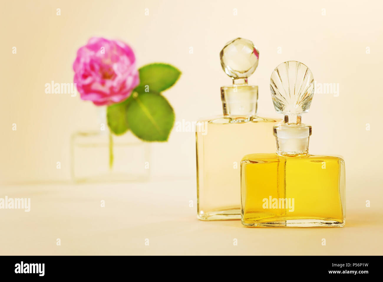 Two vintage bottles of perfume with the glass stoppers and red rose in ...