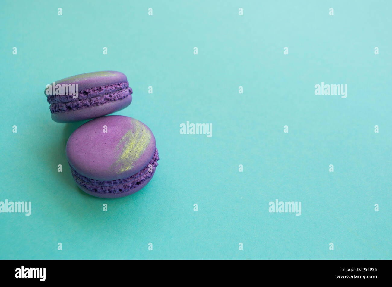 Two beautiful and tasty violet color macaroons with golden stroke on ...