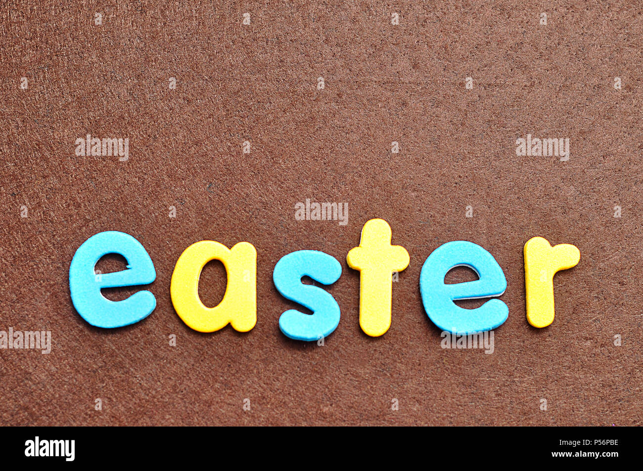 The word easter spelled with yellow and blue letters on a brown ...