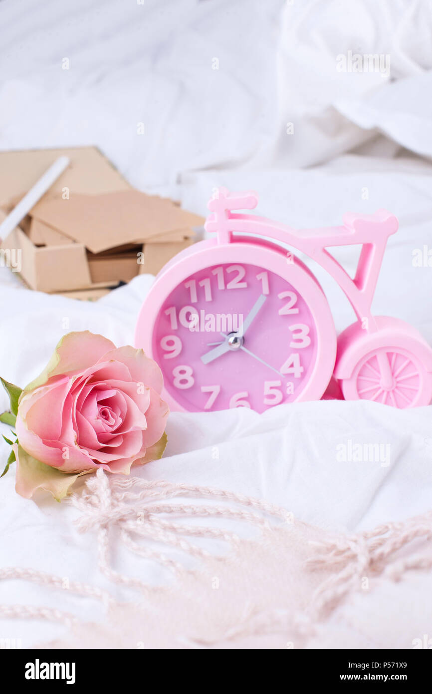 Pink alarm clock, white bed and pink roses. Good morning Vintage photo ...