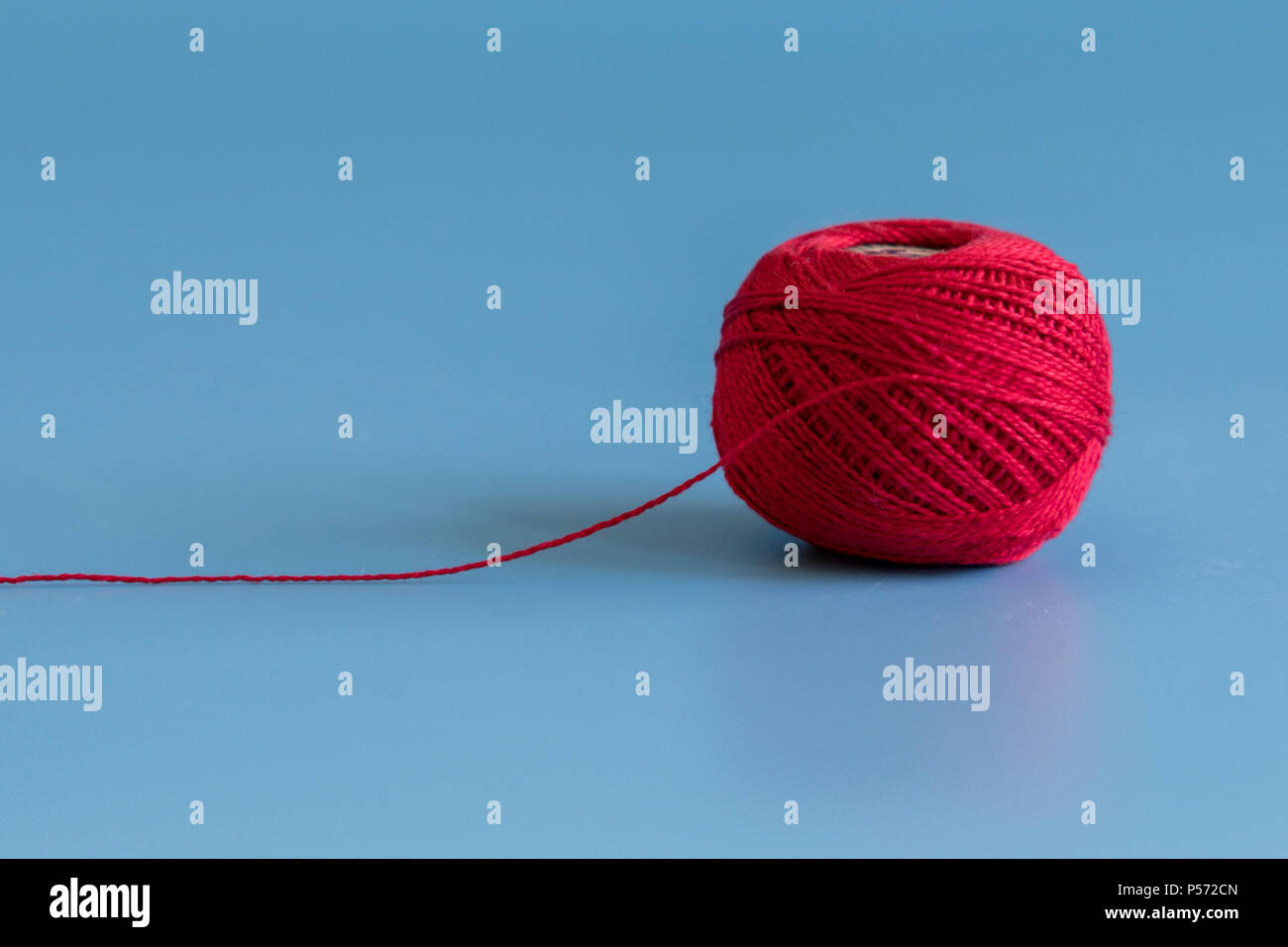 Red tangle of thread on a blue background Stock Photo - Alamy