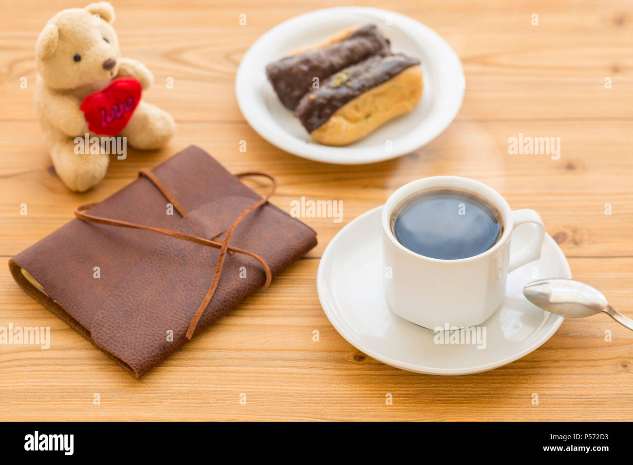Hot coffee with steam and leather journal, teddy bear, and some eclairs ...