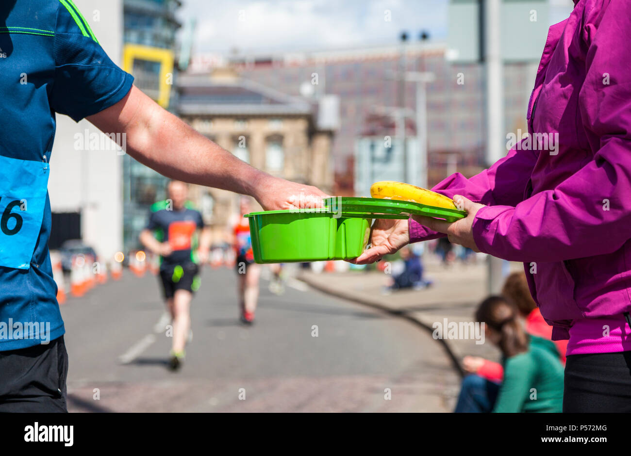 Marathon runner reaches for refreshment while running past Stock Photo ...