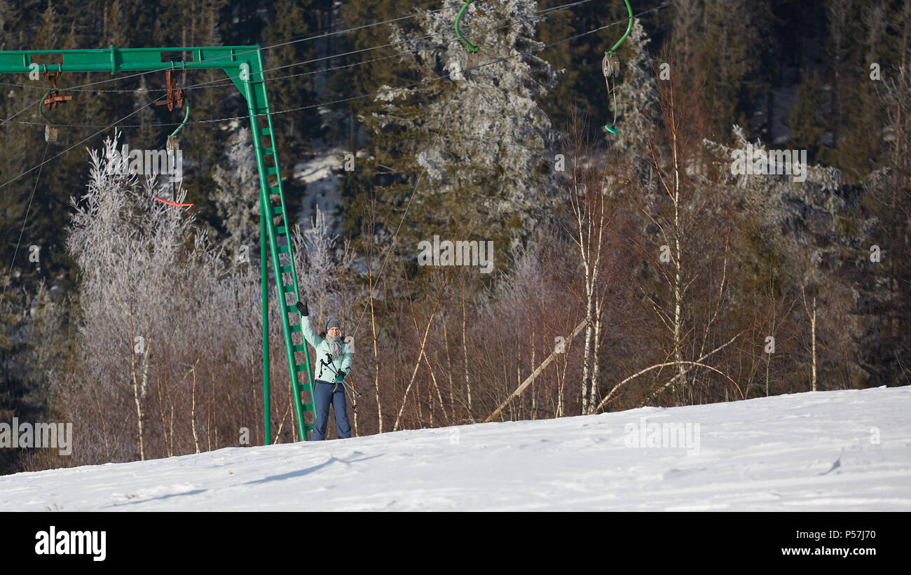Happy young woman on button ski lift going uphill Stock Photo - Alamy