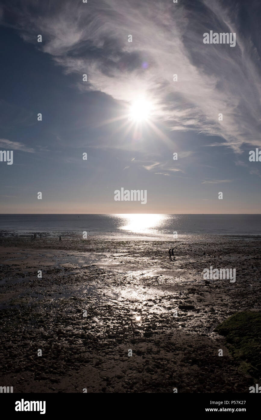 Sun setting over a beach with distant figures silhouetted Stock Photo ...