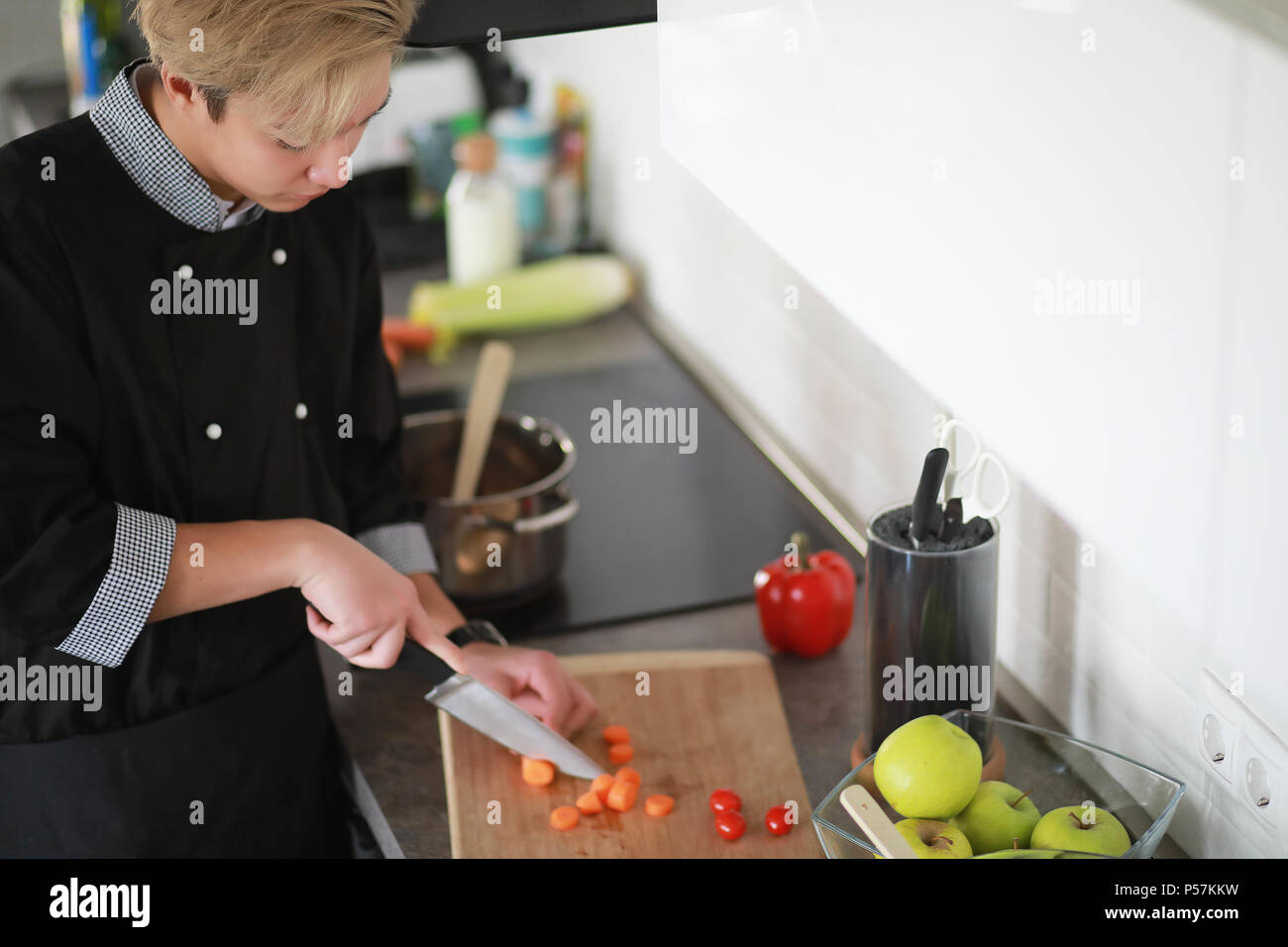 A young Asian cook in the kitchen prepares food in a cook suit Stock ...
