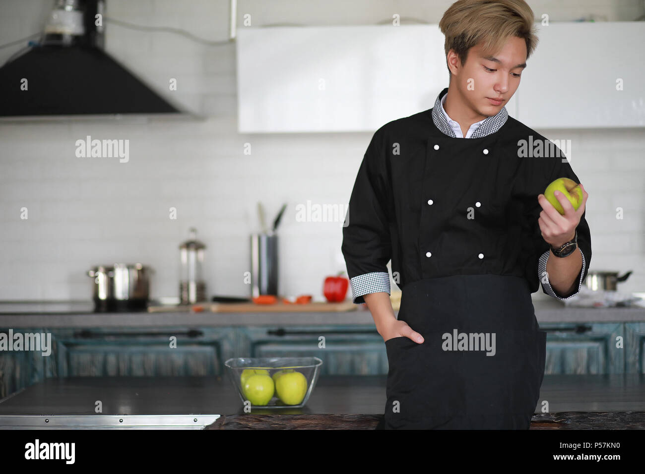 A young Asian cook in the kitchen prepares food in a cook suit Stock ...