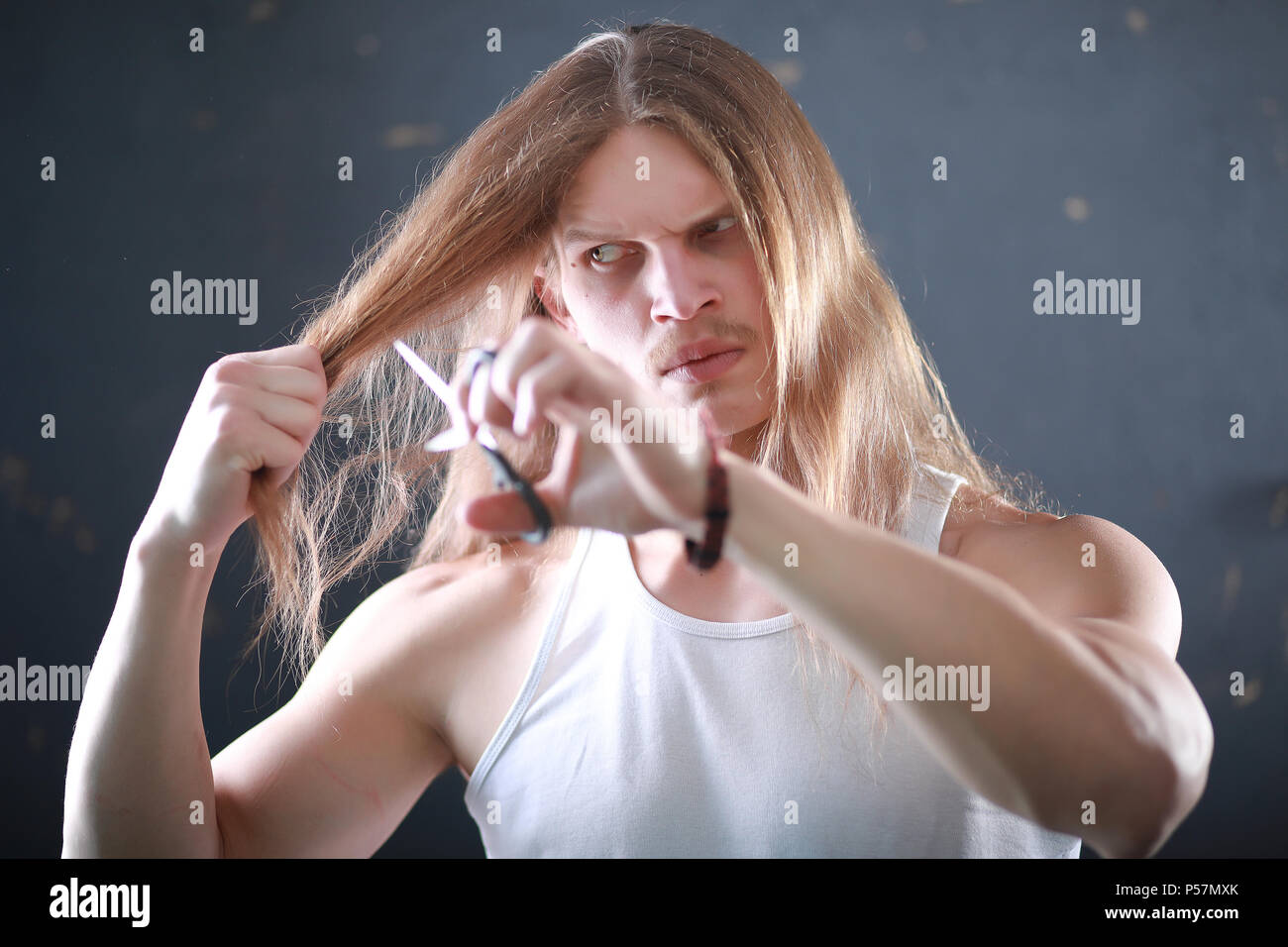 A young man with long hair wants to cut himself a lock Stock Photo - Alamy