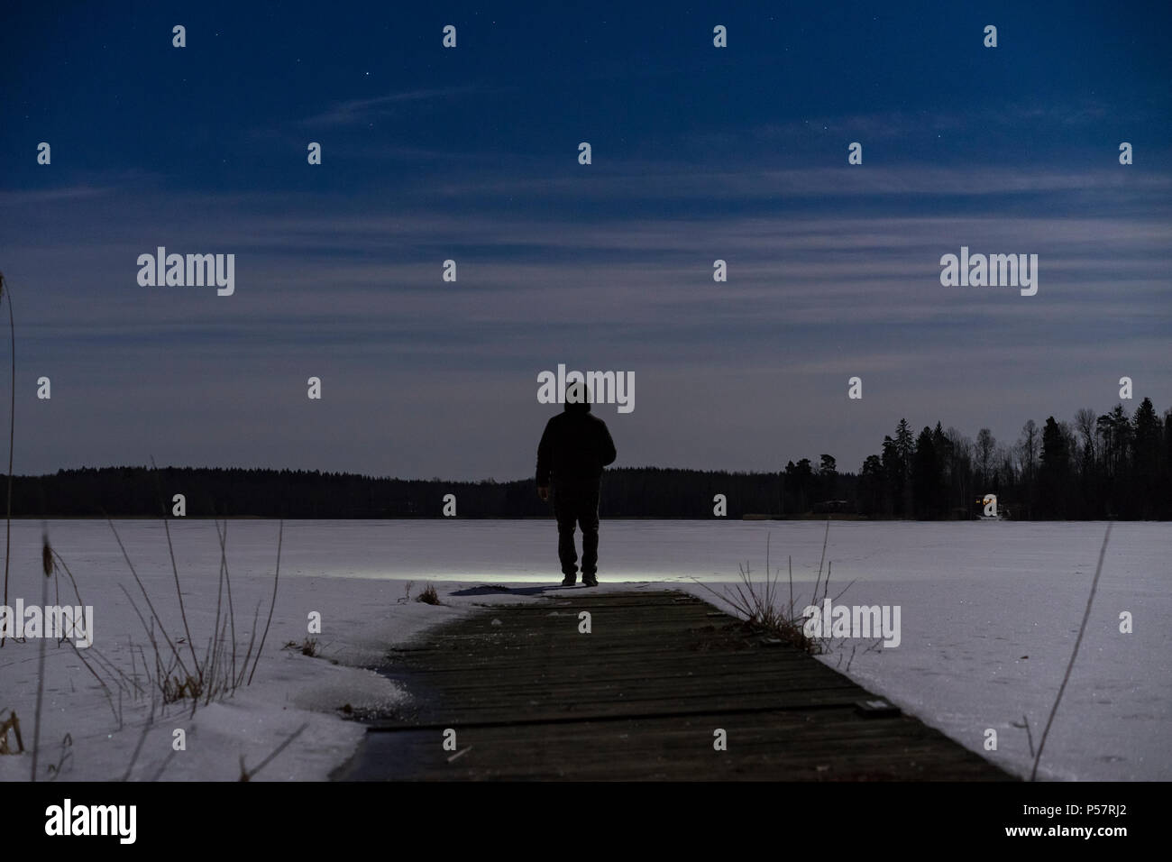 Human standing outdoor at night with flashlight and hoodie on head ...