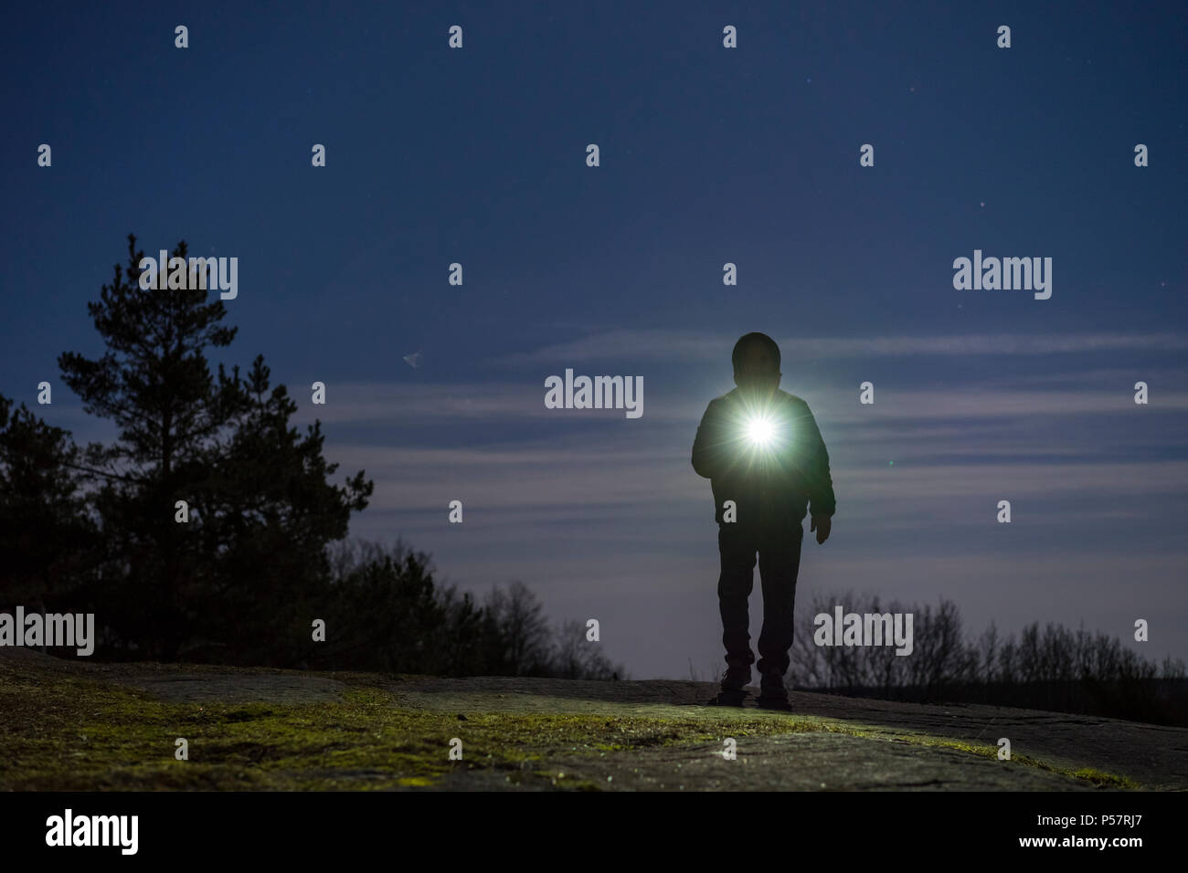Human standing outdoor at night with flashlight and hoodie on head ...