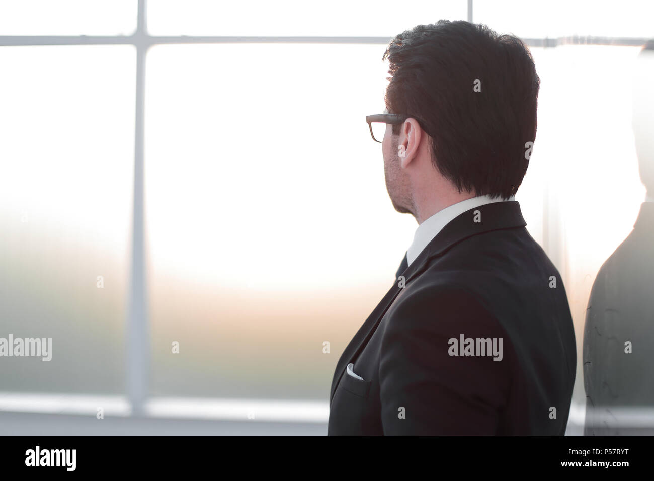 side view. businessman standing near the office window Stock Photo - Alamy