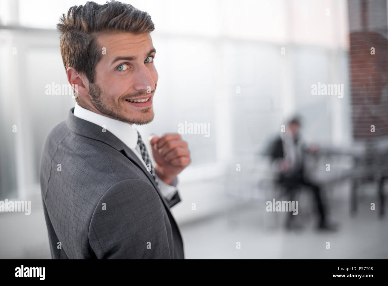 close up.smiling businessman standing in front of the office window ...