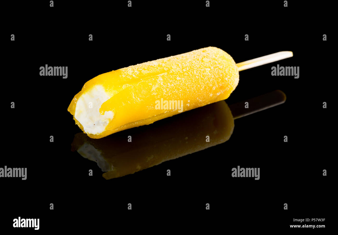studio shoot yellow popsicle on a black background with some bites ...