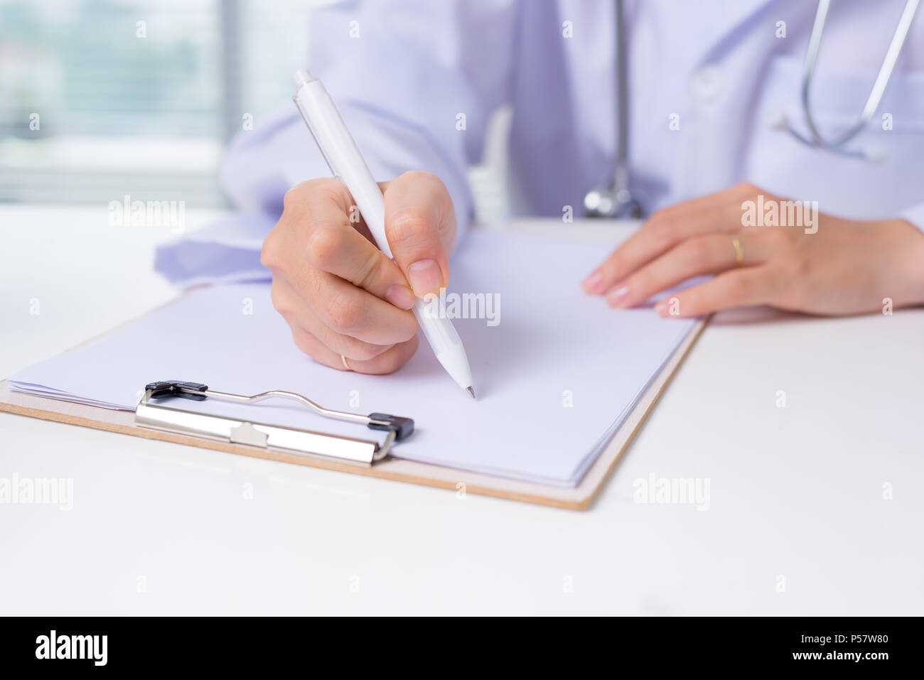 Close up on asian female doctor hands writing something on clipboard ...
