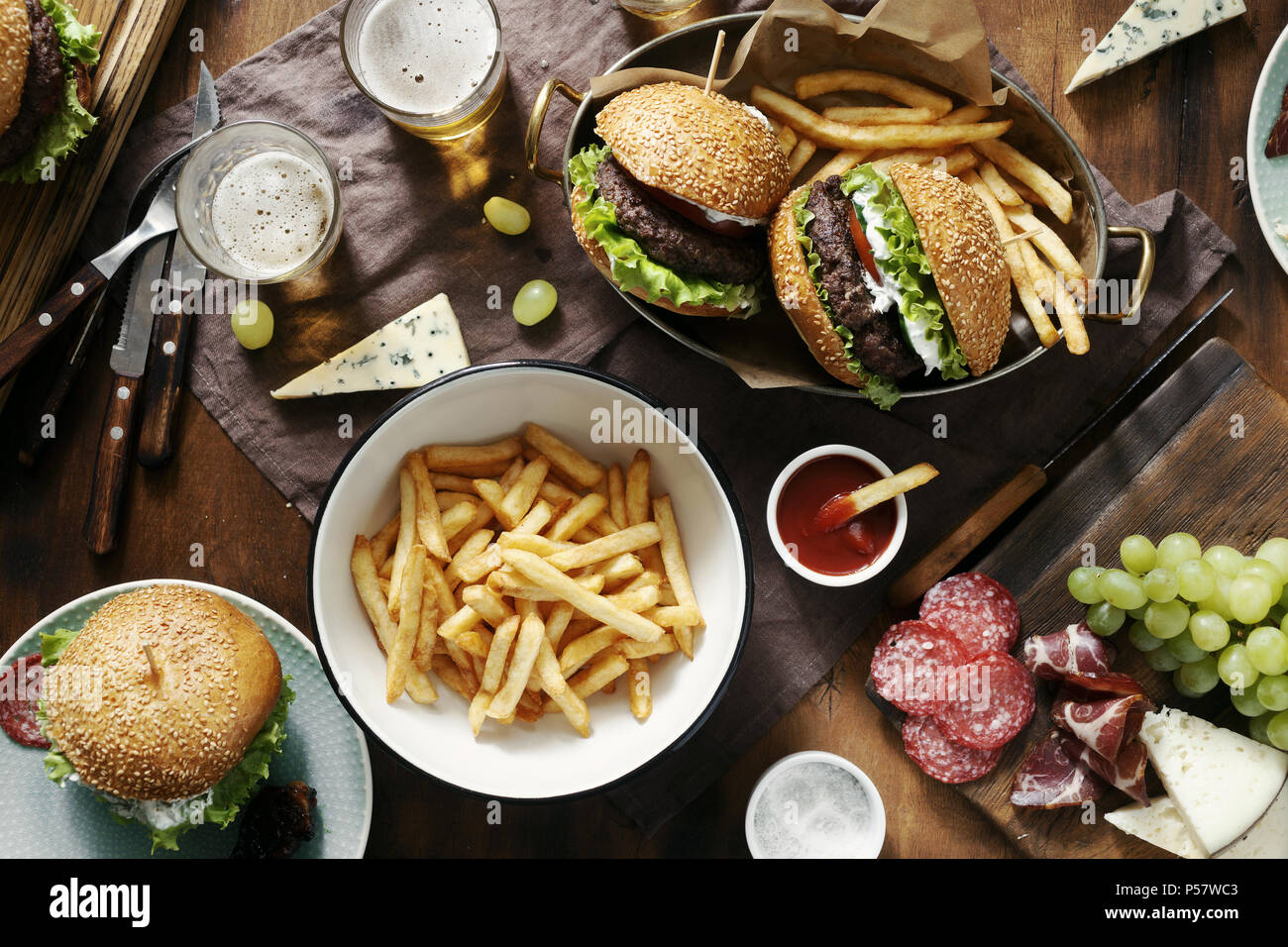 Burgers and french fries served in frying pans on wooden table with ...