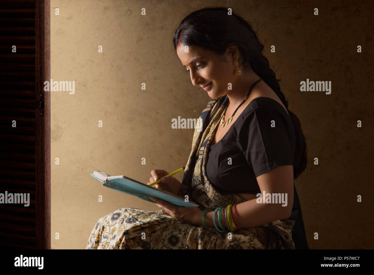 Indian rural woman writing in book with pencil Stock Photo - Alamy
