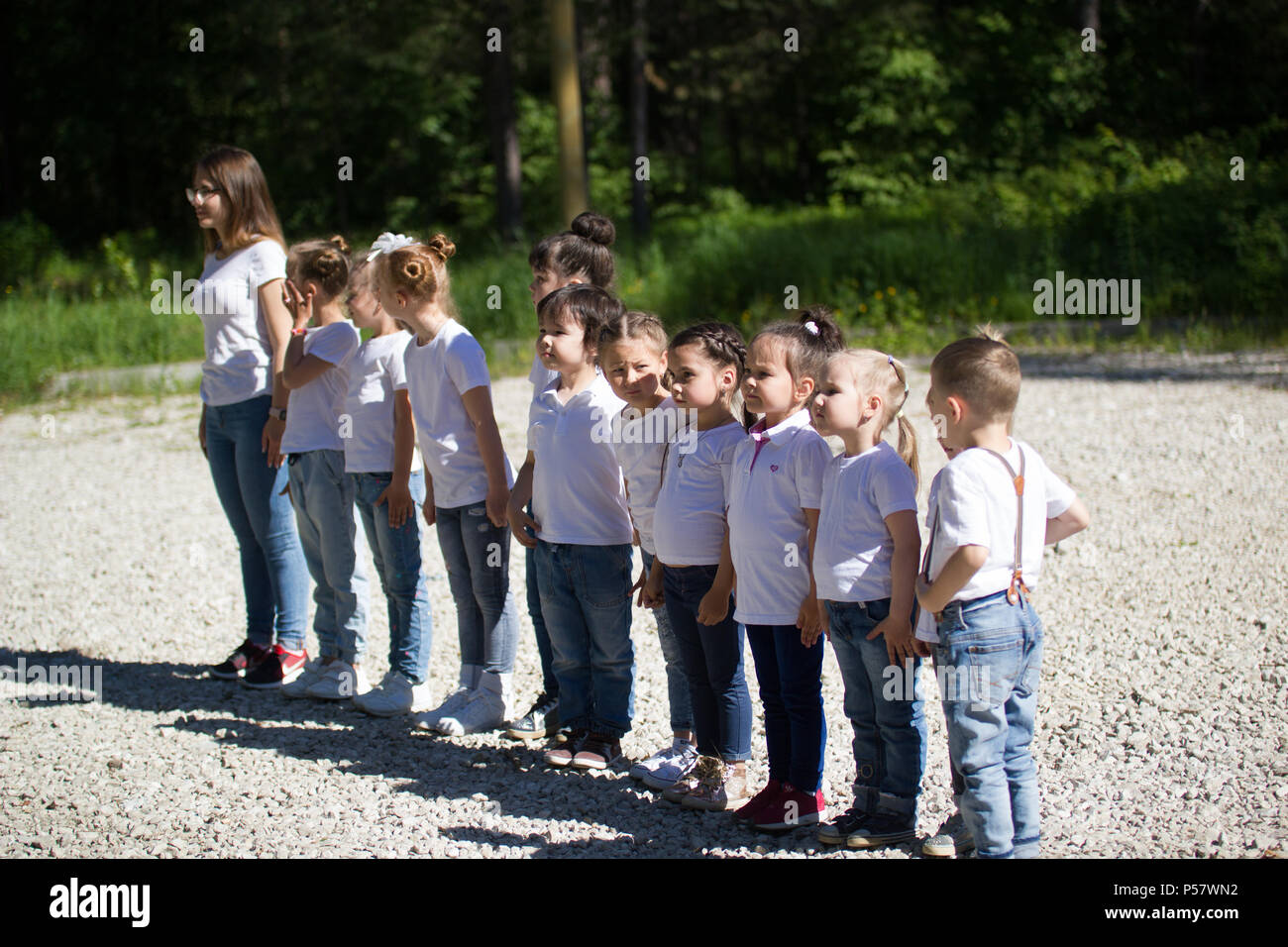 Group of little children different ages lined up in line in summer park ...