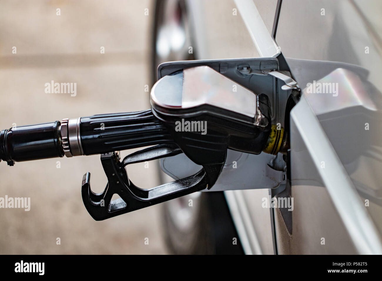 white car is refueled to a gas station, a refueling gun in the filler ...