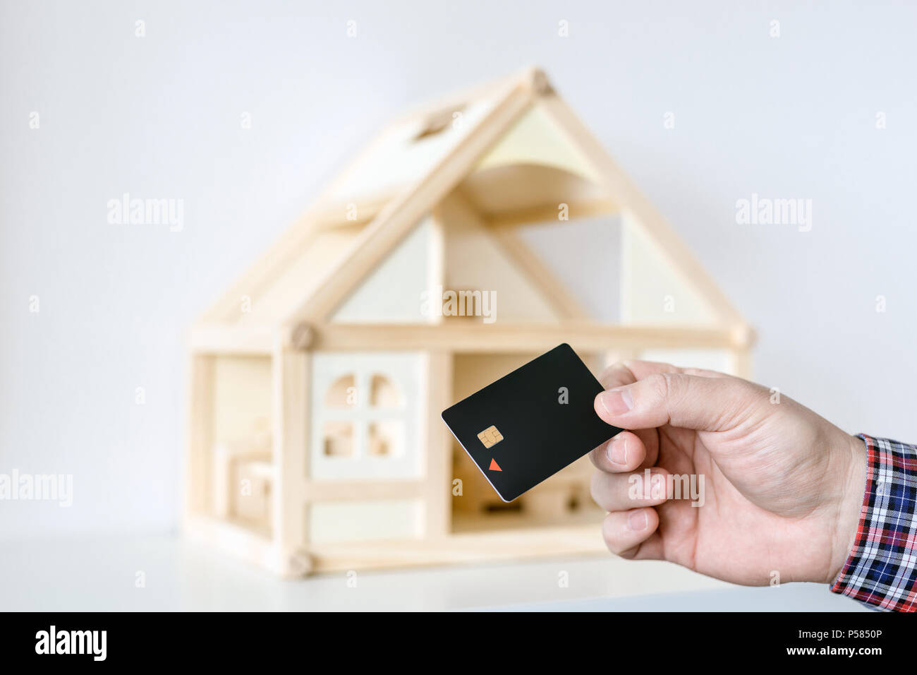 Hand holding black plastic chip keycard. Wooden house model on ...