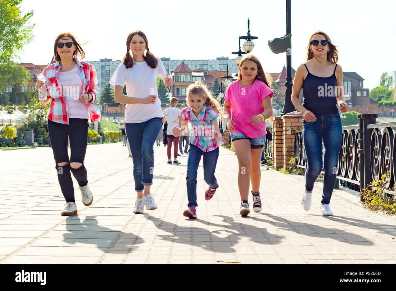 Group of mothers and daughters are running along the road in the park ...