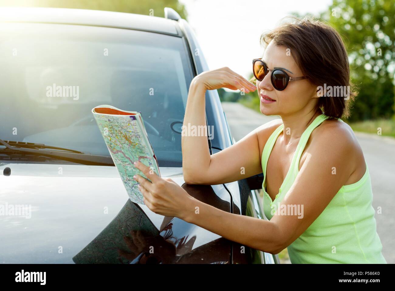 Cute female driver is traveling. Standing beside his car on a country ...