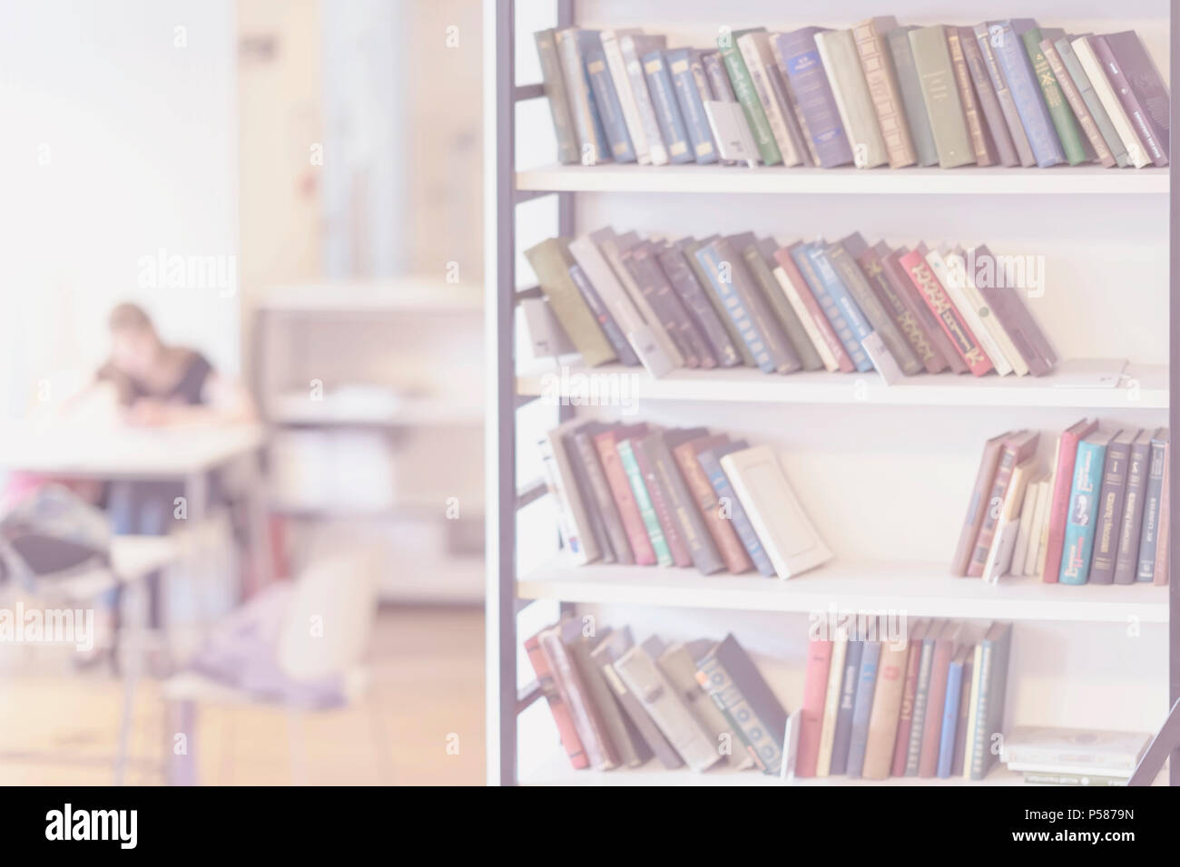Abstract blurred young girl sitting reading book in public library ...