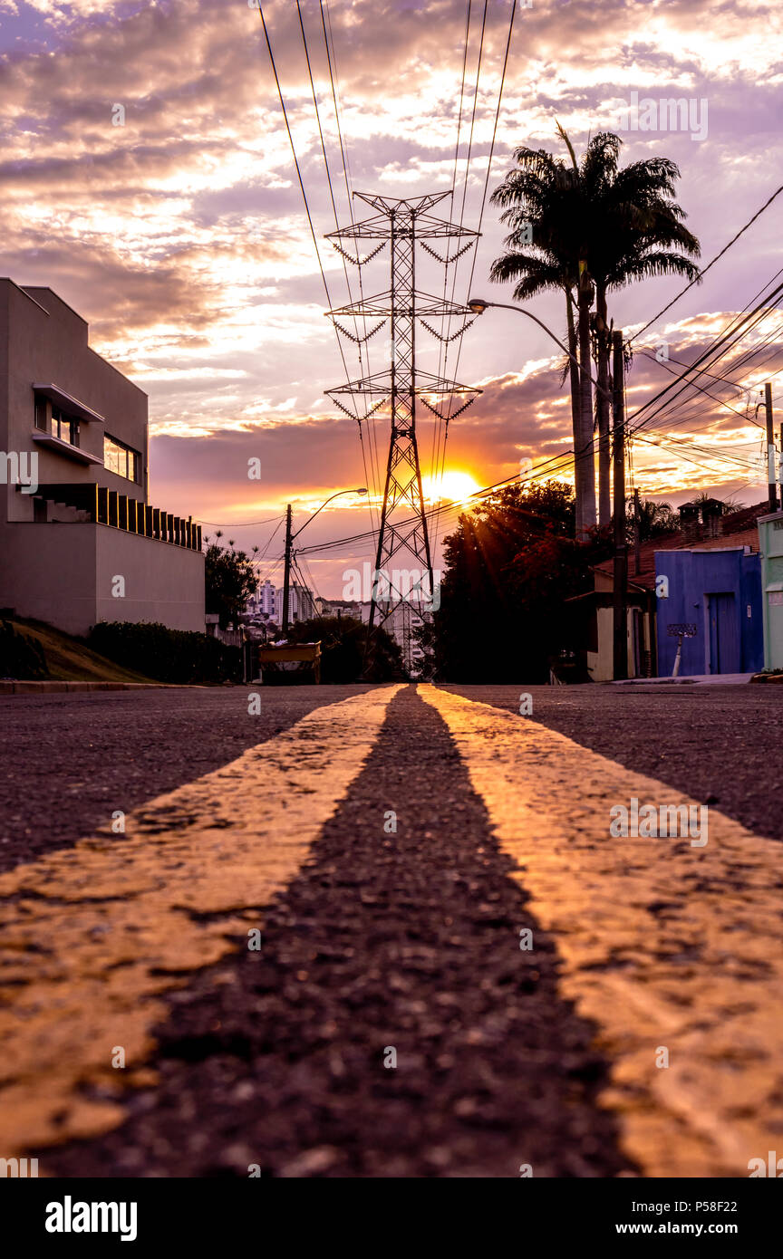 Street leading to a high voltage power tower against sunset sky Stock ...