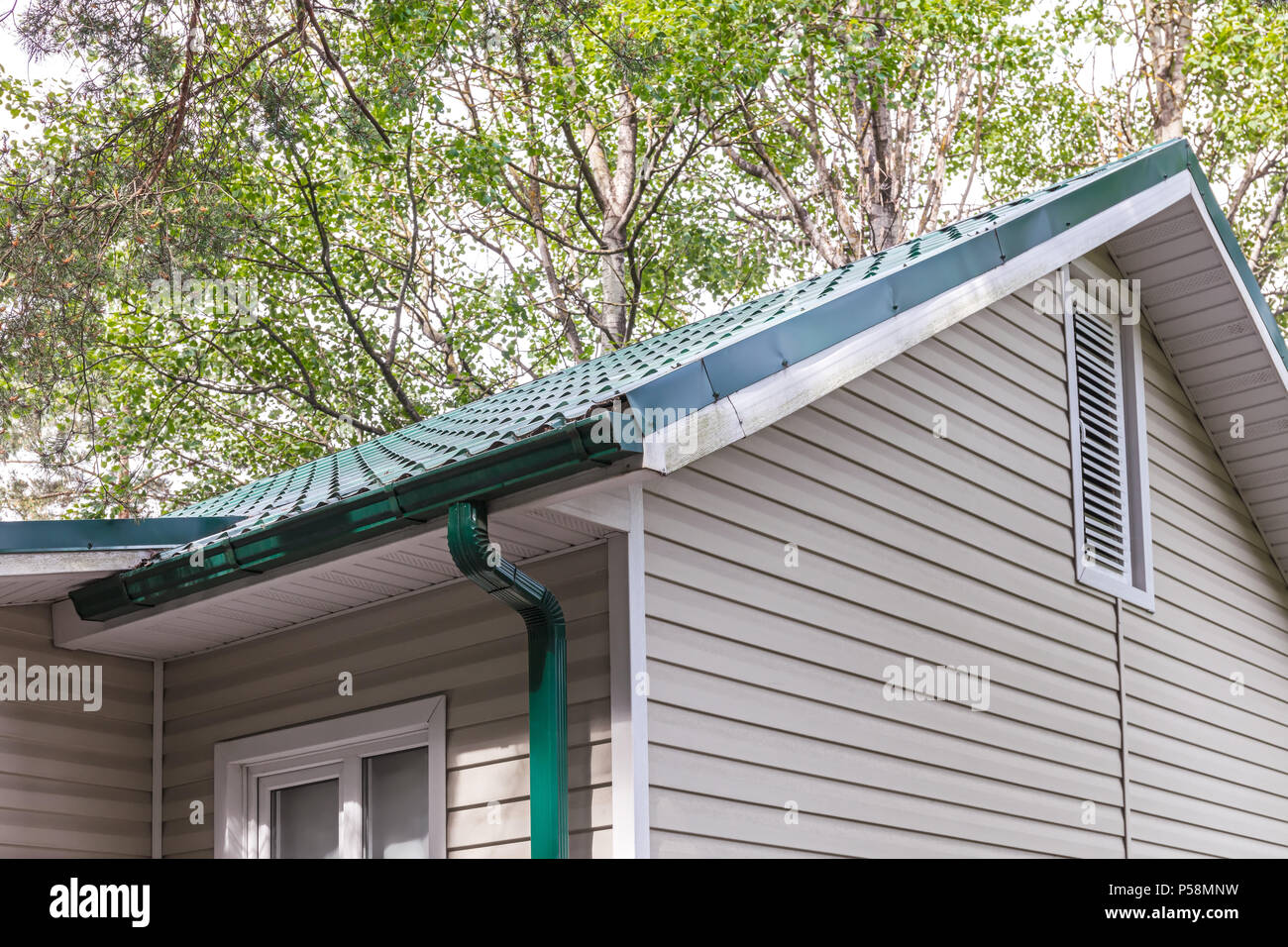 rain gutter system and tiled roof against green trees background Stock ...