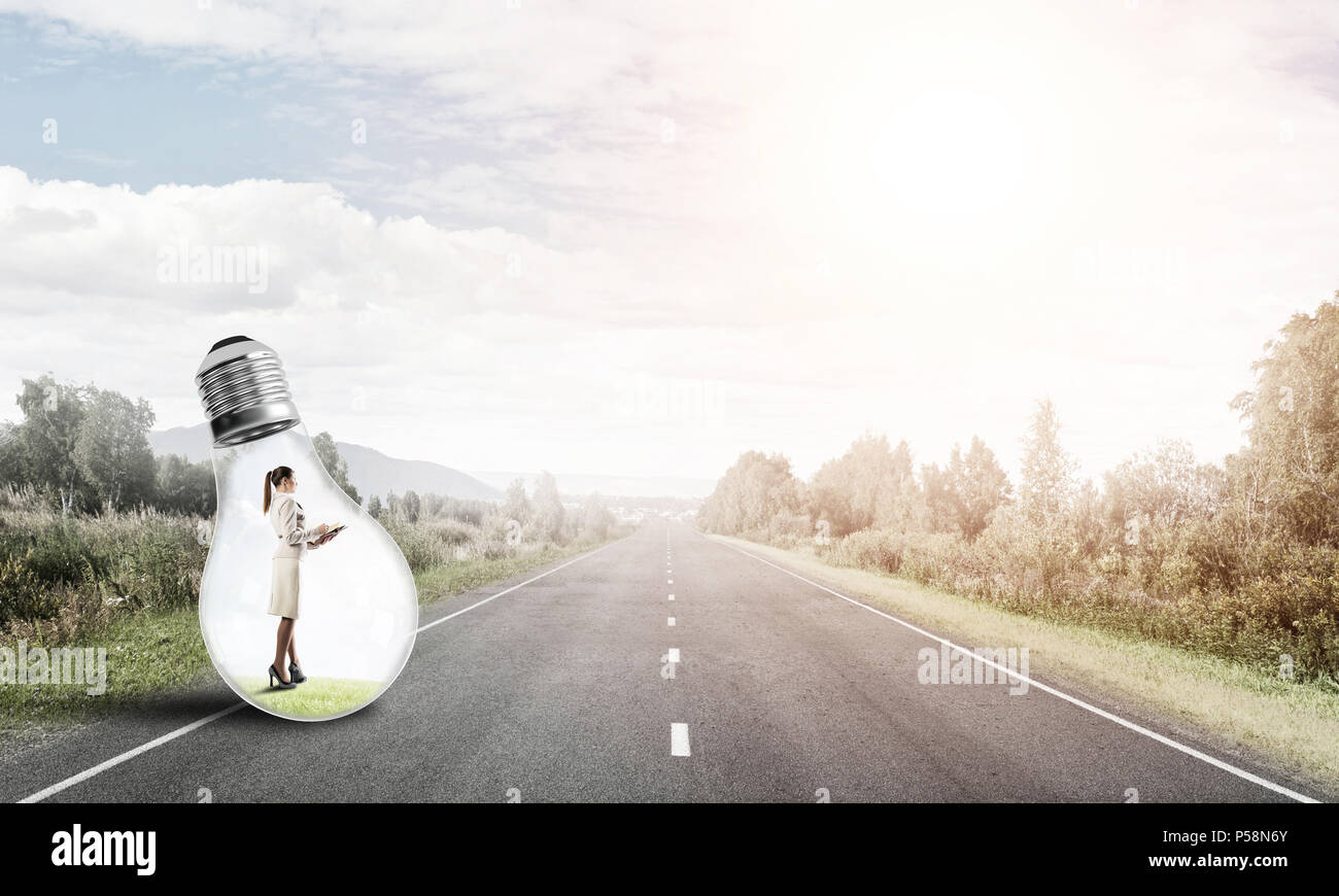 Young businesswoman trapped inside of light bulb on asphalt road Stock ...