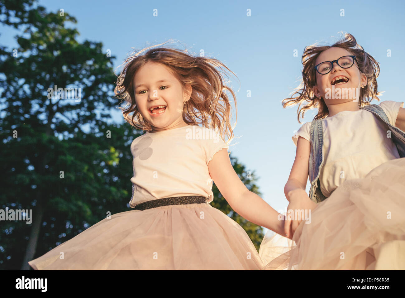 Two joyful girls running, jumping and smiling. Summer activity and ...