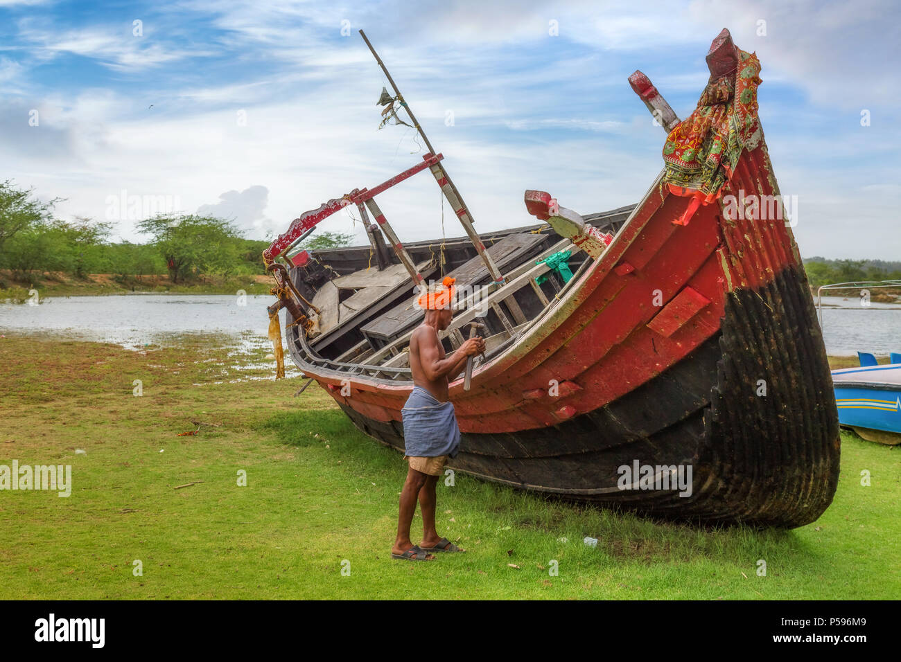 Rural fisherman working on his fishing boat near an estuary at ...