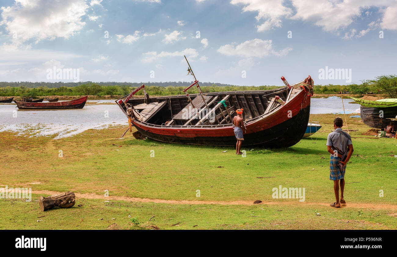 Rural fisherman working on his fishing boat near an estuary at ...