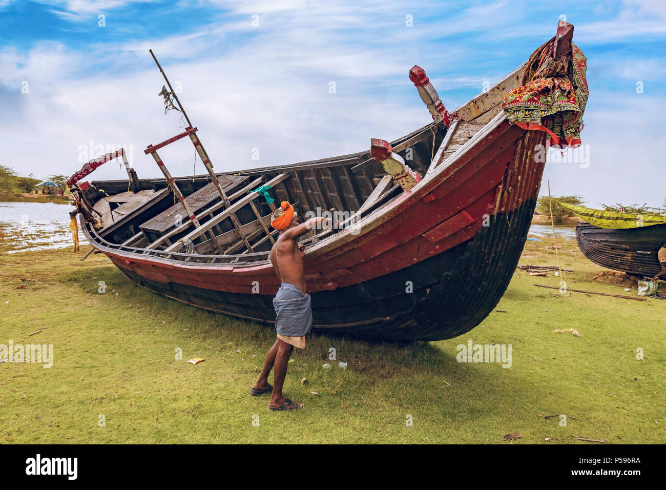 Rural fisherman working on his fishing boat near an estuary at ...