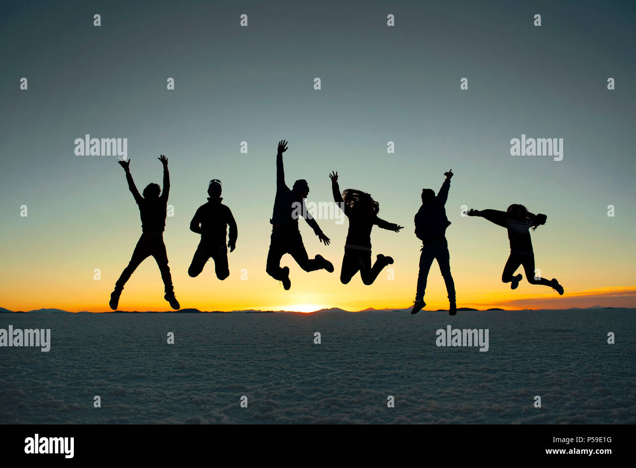 Dynamic team jump in magical sunset. Salar de Uyuni, Bolivia Stock ...