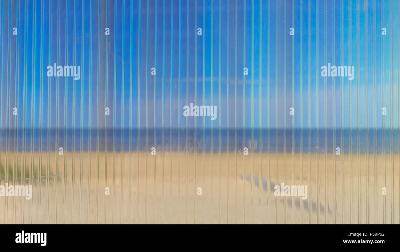 Blue sea and yellow beach through corrugated plastic transparent sheet ...