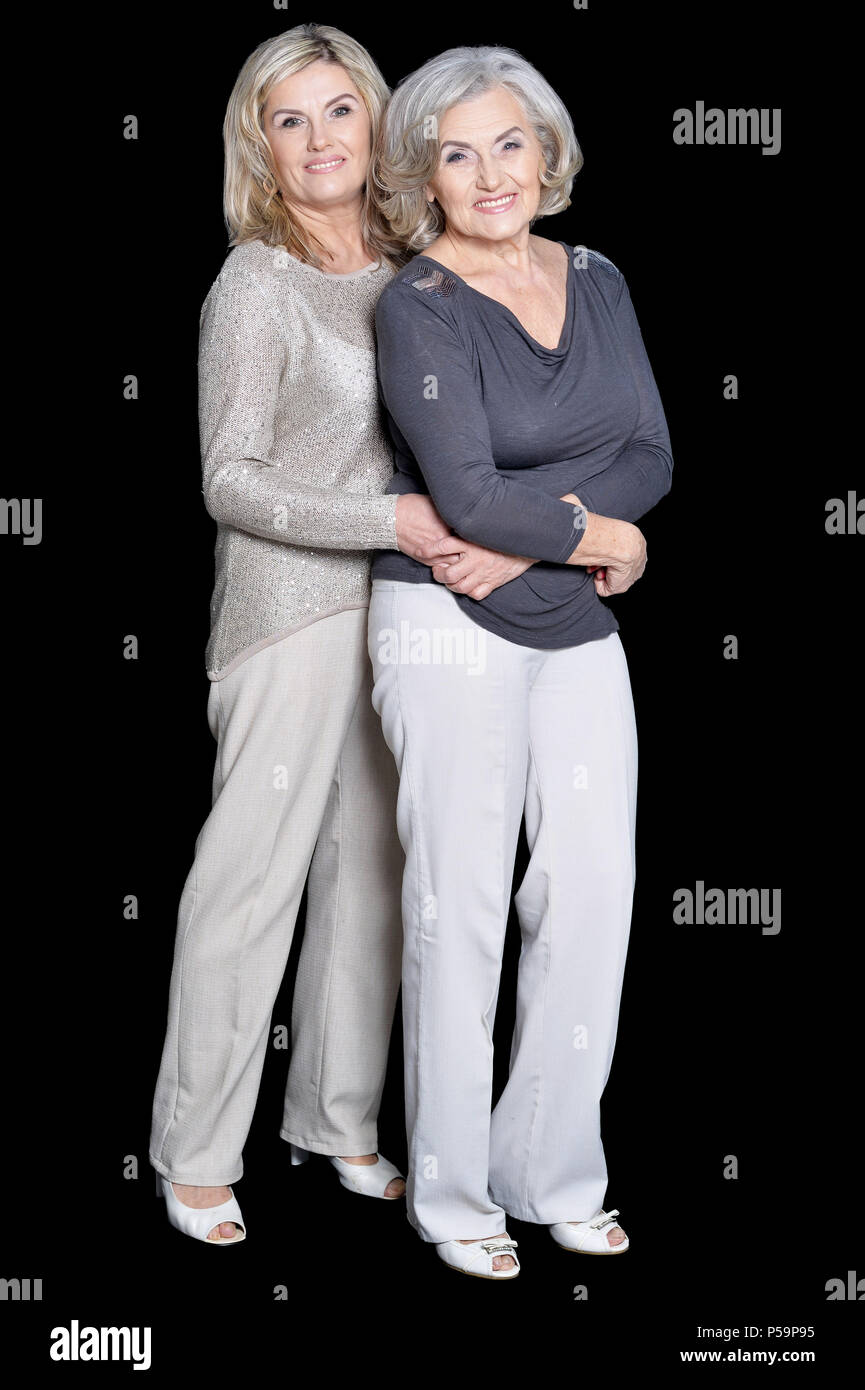 two beautiful senior women posing against black background Stock Photo ...