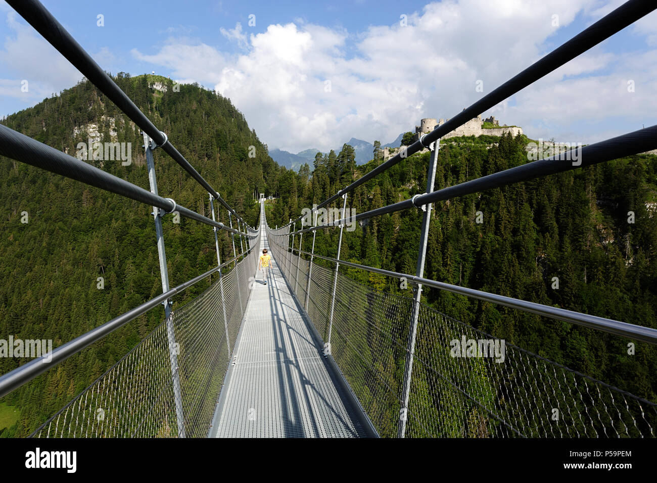 Young boy in yellow t-shirt walking on suspension bridge Highline 179 ...