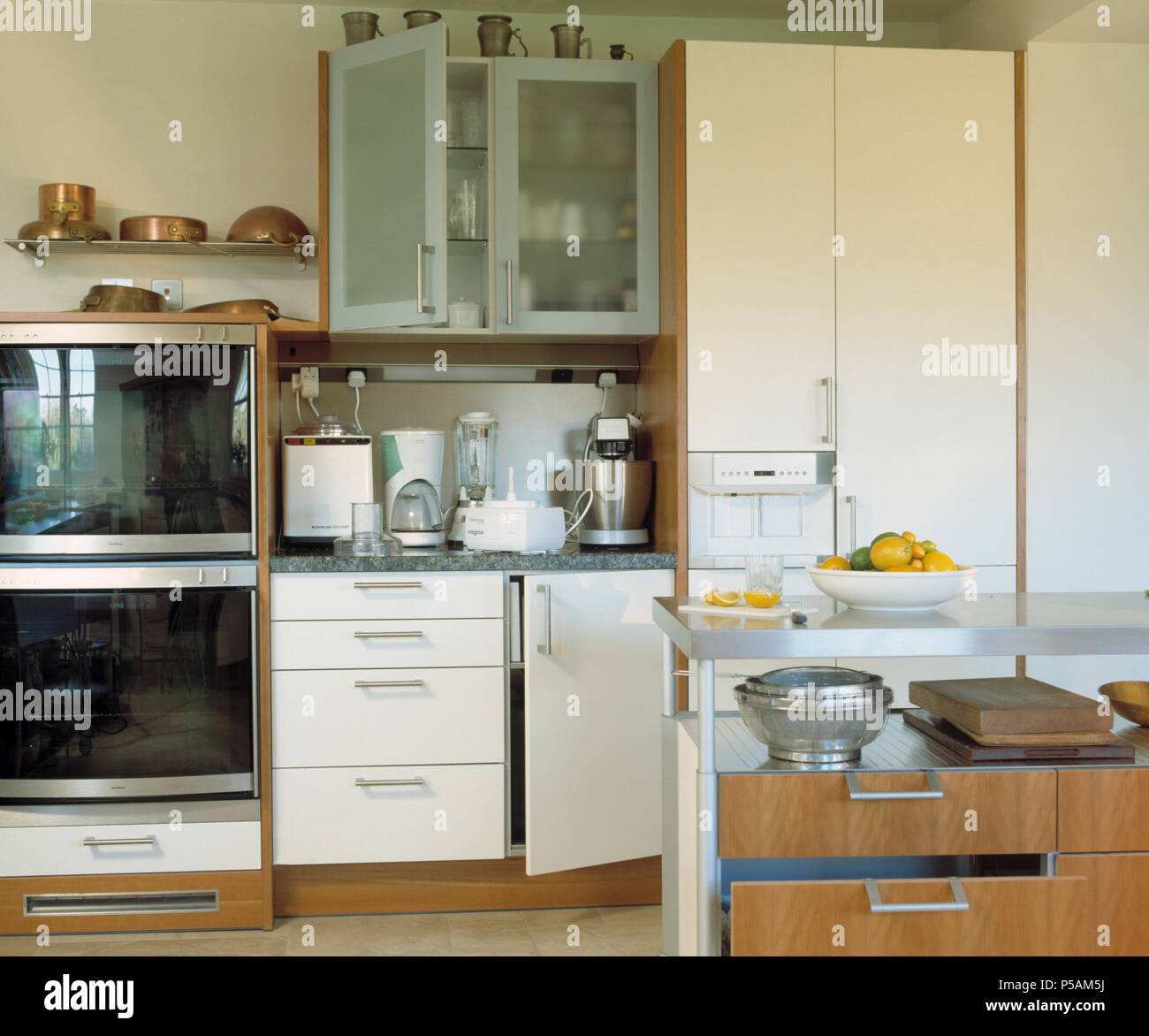 Electric appliances on worktop below cupboard with opaque glass doorts ...